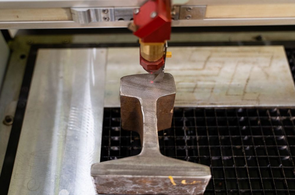 Bechtel student employees demonstrate laser engraving skills on steel rails
